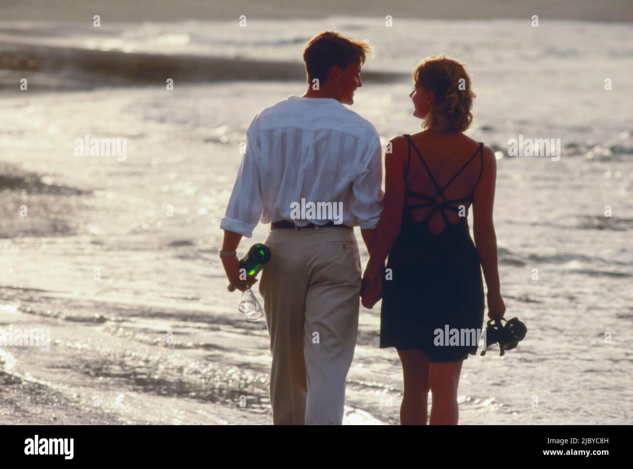 Back view of couple with champagne walking along the beach Stock Photo ...