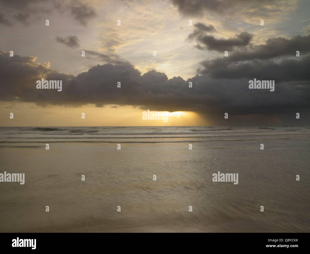 Last of suns rays shining from behind grey clouds over the ocean Stock ...