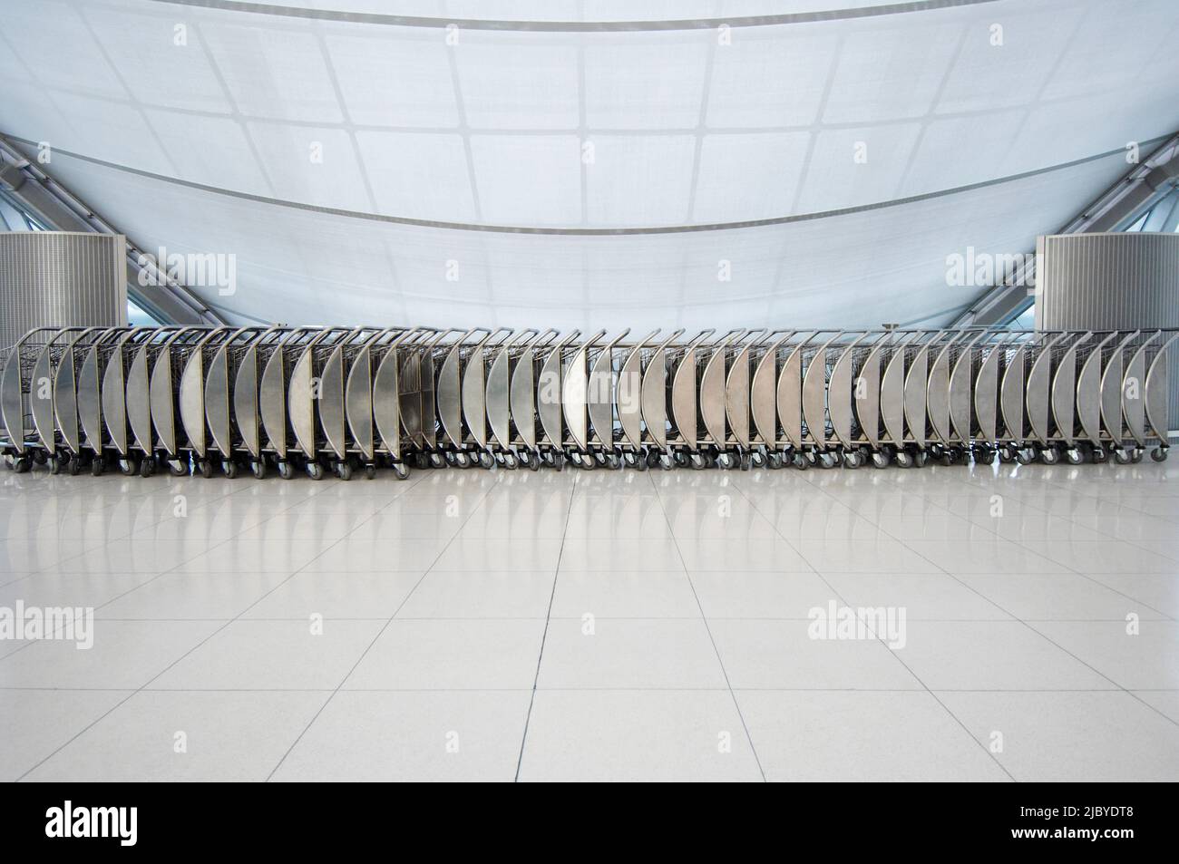 Neatly stacked row of stainless steel airport baggage carts placed ...
