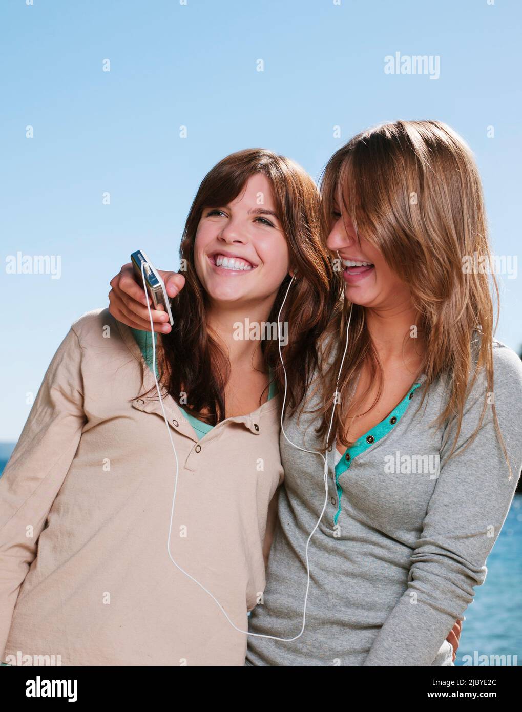 Two teenage girls sharing earbuds, listening to music Stock Photo - Alamy