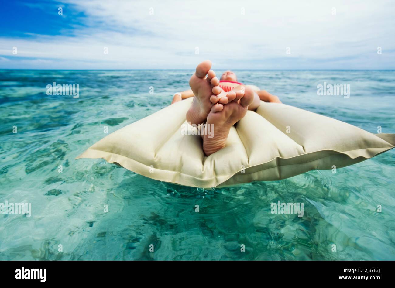 Close up view of legs and feet of woman lying on a lilo floating in ...