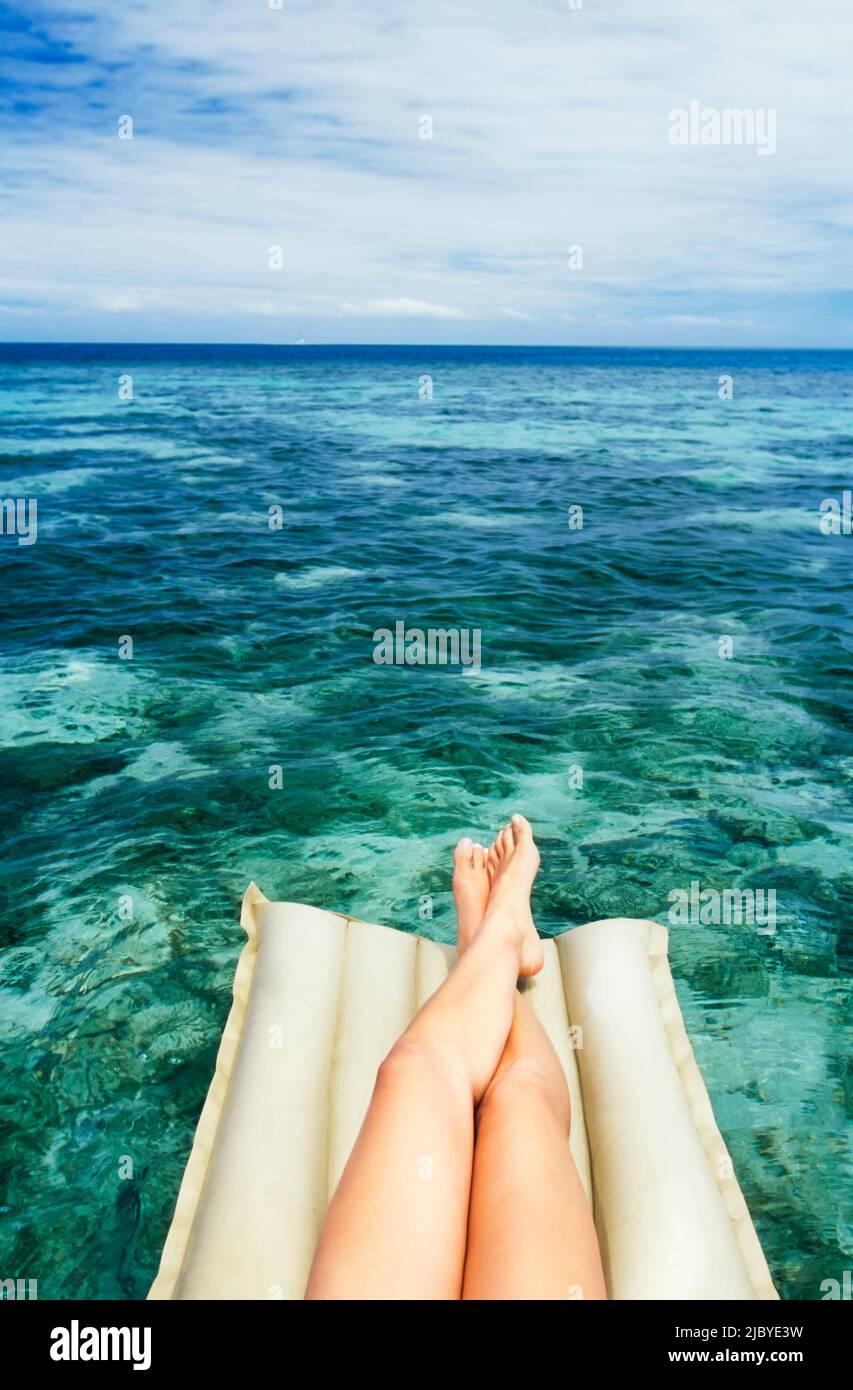 Close up view of legs and feet of a woman lying on lilo floating in ...