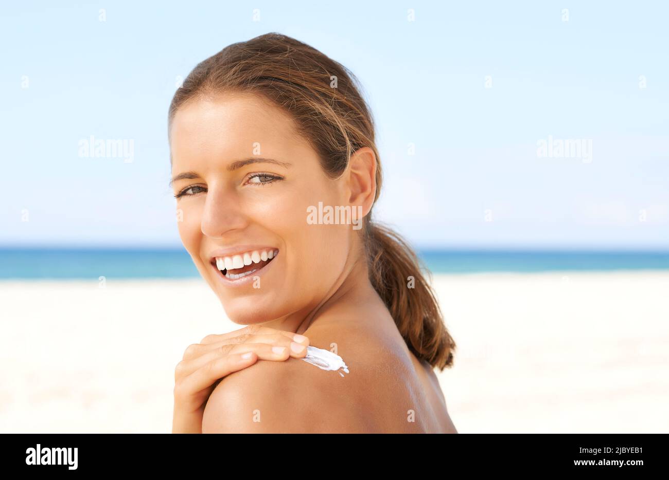 Portrait of healthy beautiful young woman applying sunscreen to her ...