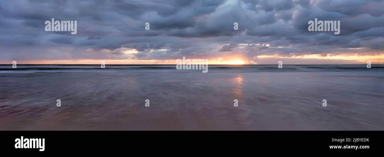 Panorama of sun setting on the horizon where the sea meets the stormy ...