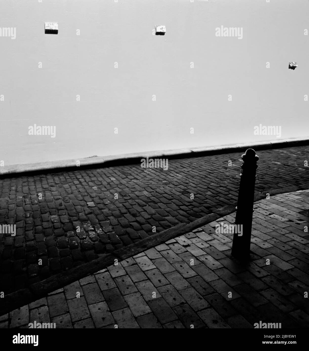 Cobbled road butting up to concrete wall of building Stock Photo - Alamy