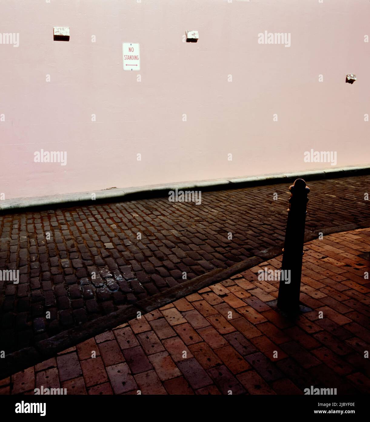 Cobbled road butting up to concrete wall of building painted pink Stock ...