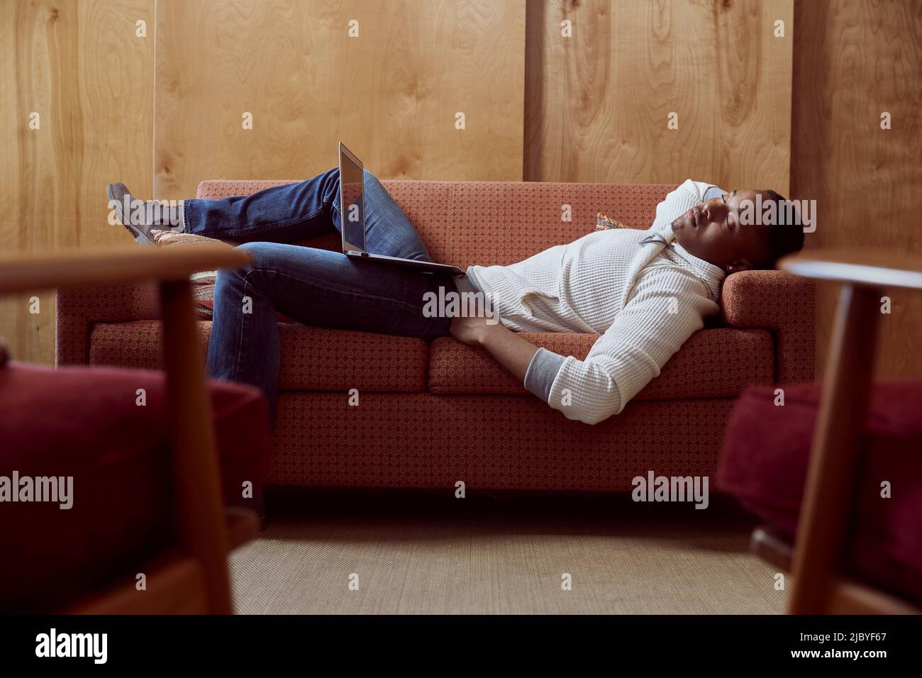 Young man taking a nap on loveseat with his computer on his lap Stock ...