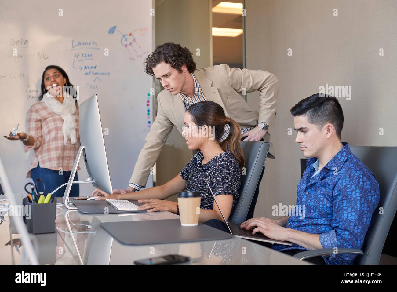 Co-Workers talking at computer in office while woman is working on dry ...