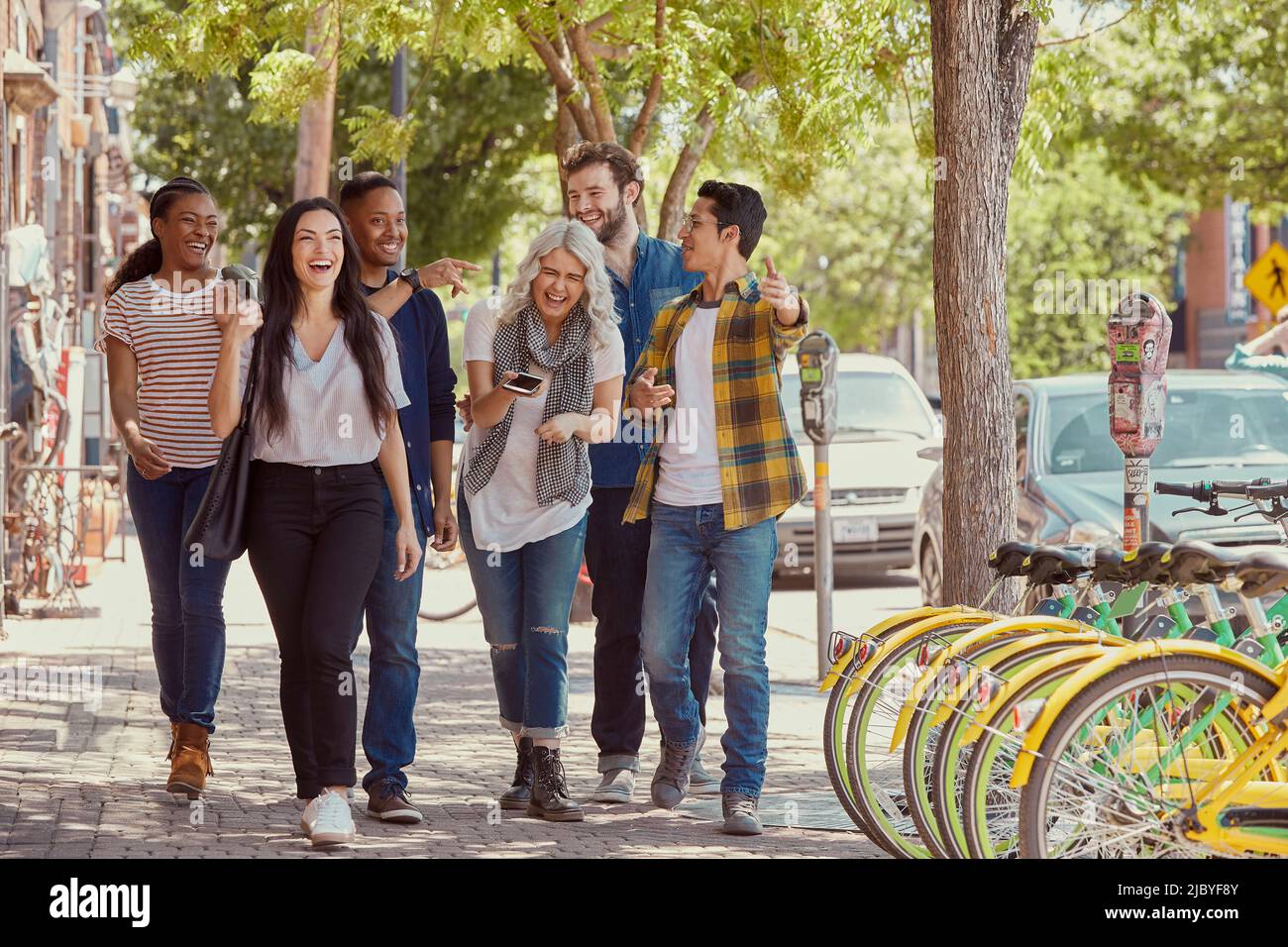 Group of young co-workers walking down sidewalk together, young woman ...