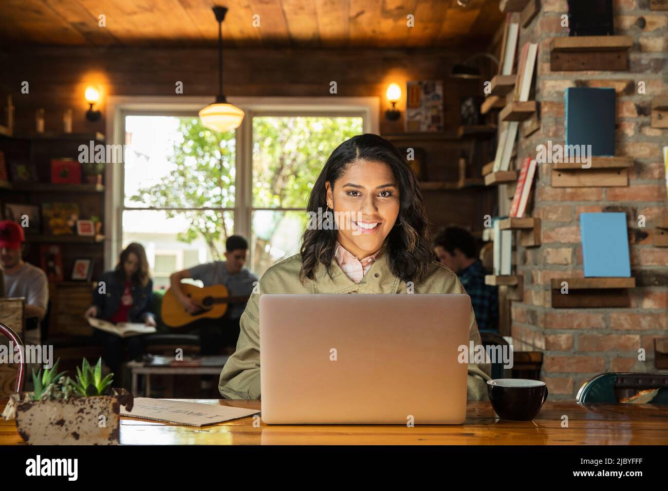 Portrait of young woman sitting at table in coffee shop bookstore using ...