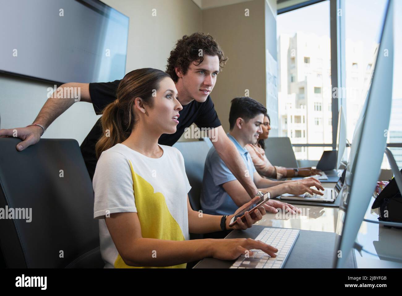 computer in office typing on keyboard and checking mobile phone ...