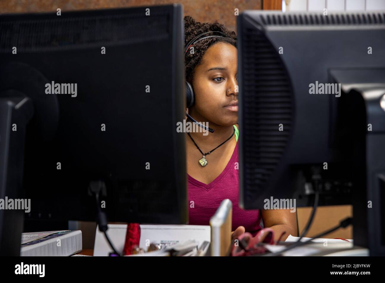 A portrait of an African American woman at her call center desk and her ...