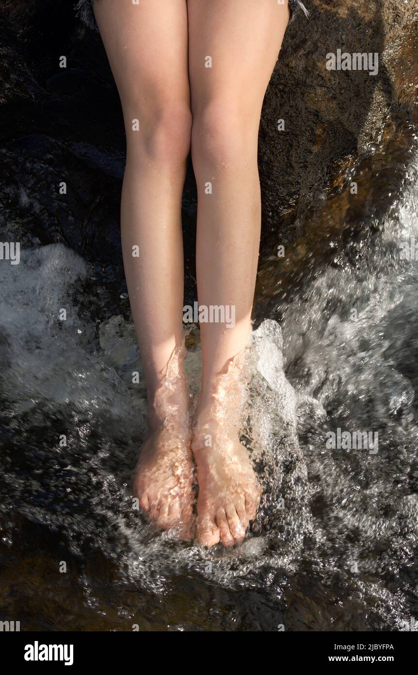 Young woman sitting on a rock and cooling feet in stream Stock Photo ...