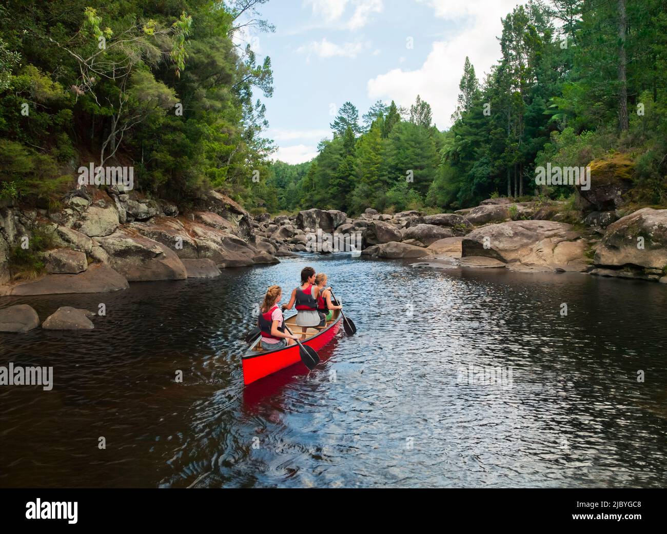 Three young adults in a canoe rowing in river in the wilderness Stock ...