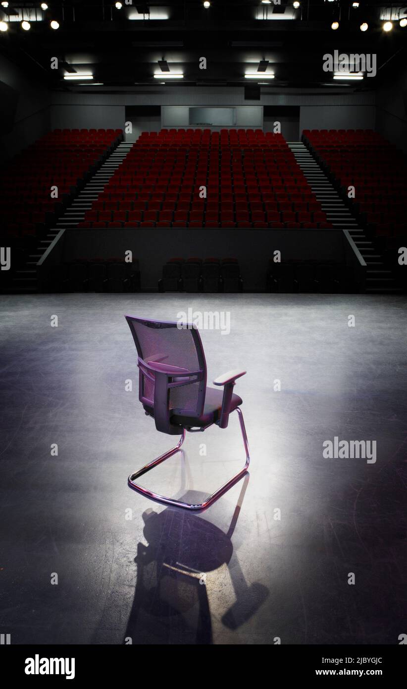 Back view of empty chair lit up on stage looking out towards empty ...