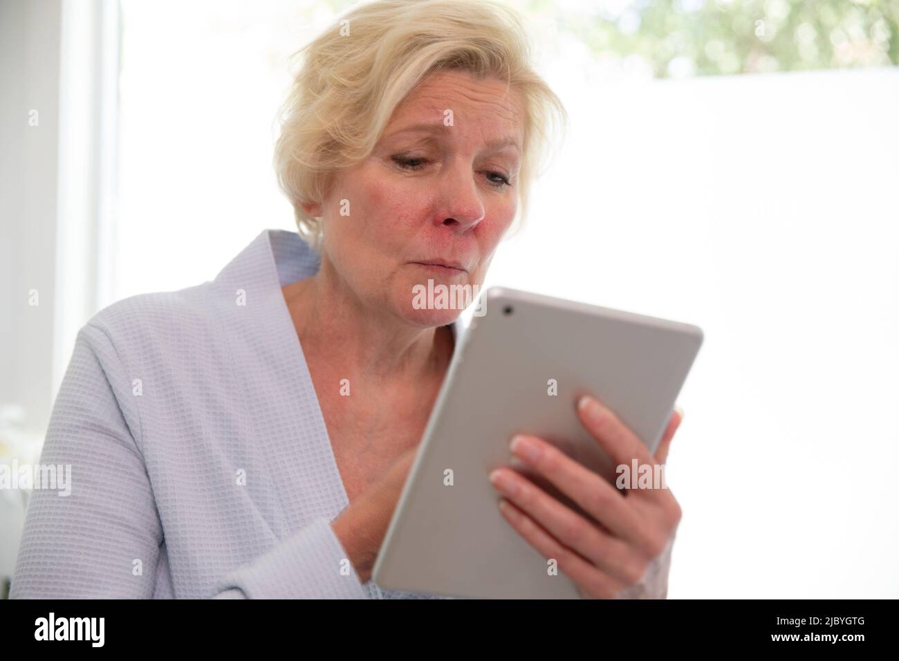 ick senior Caucasian female sitting on side of bathtub getting ready to ...