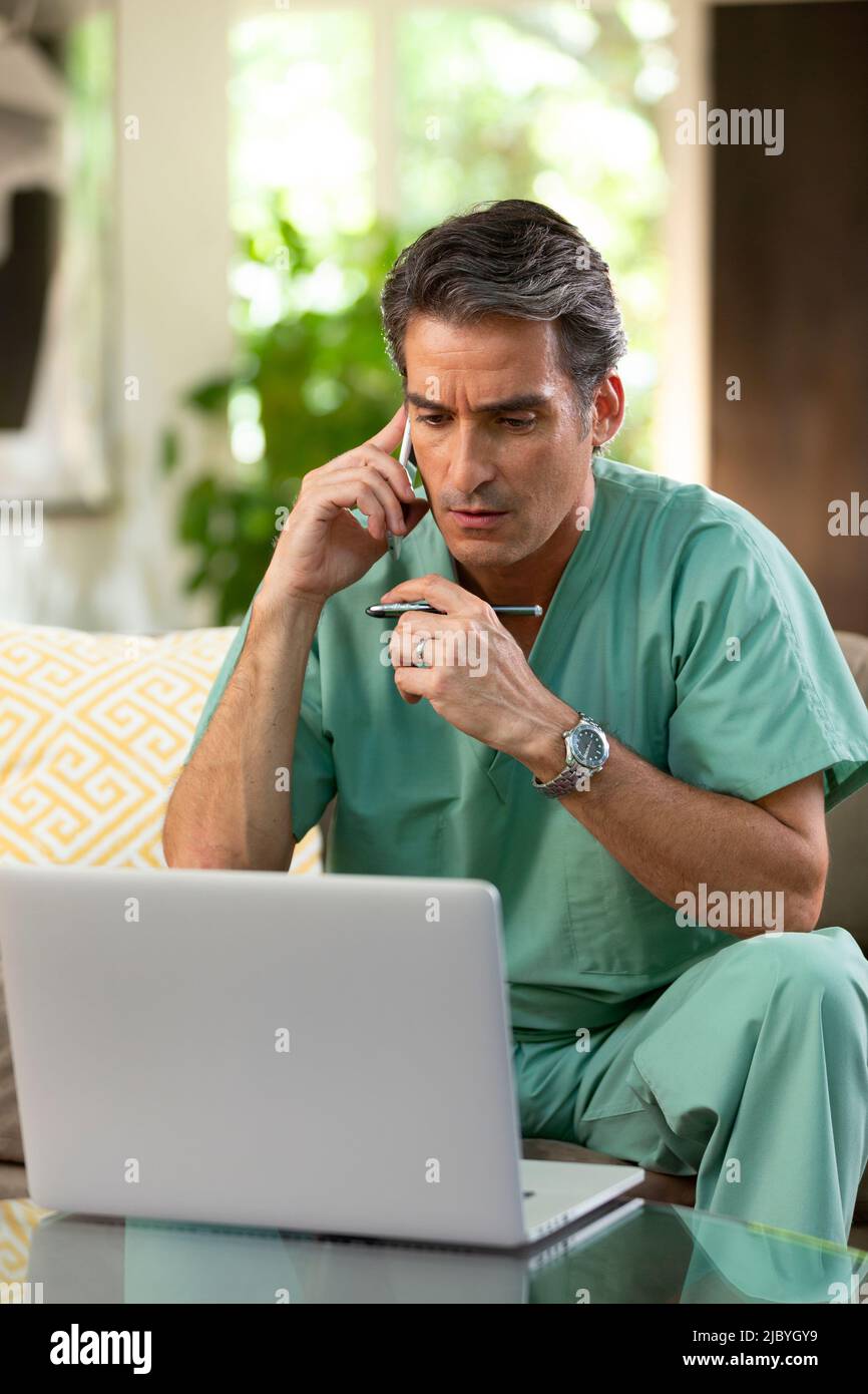 Hispanic Male doctor practicing tele-medicine from his home, using cell ...