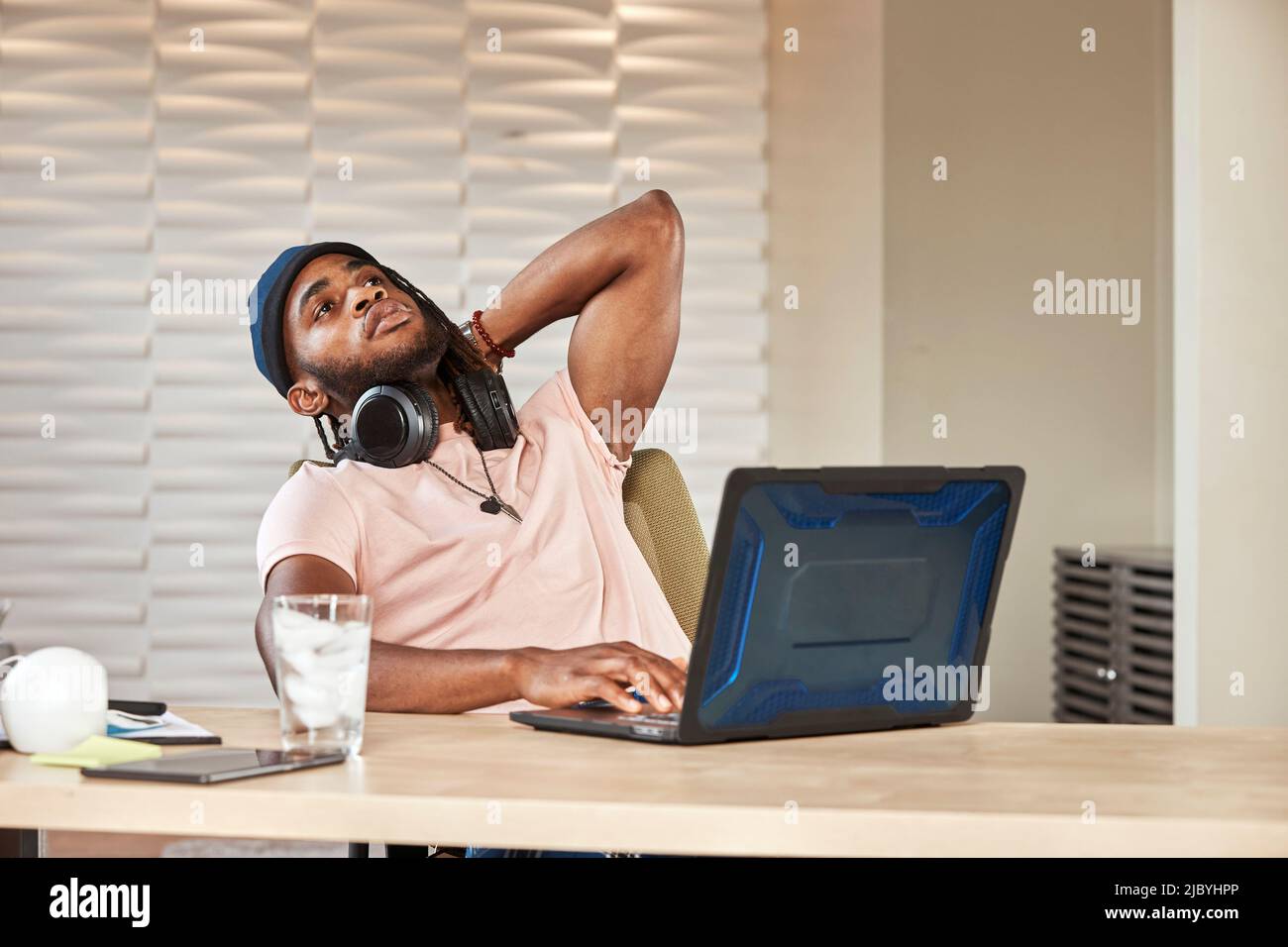 portrait young ethnic man sitting at desk with laptop computer wearing ...