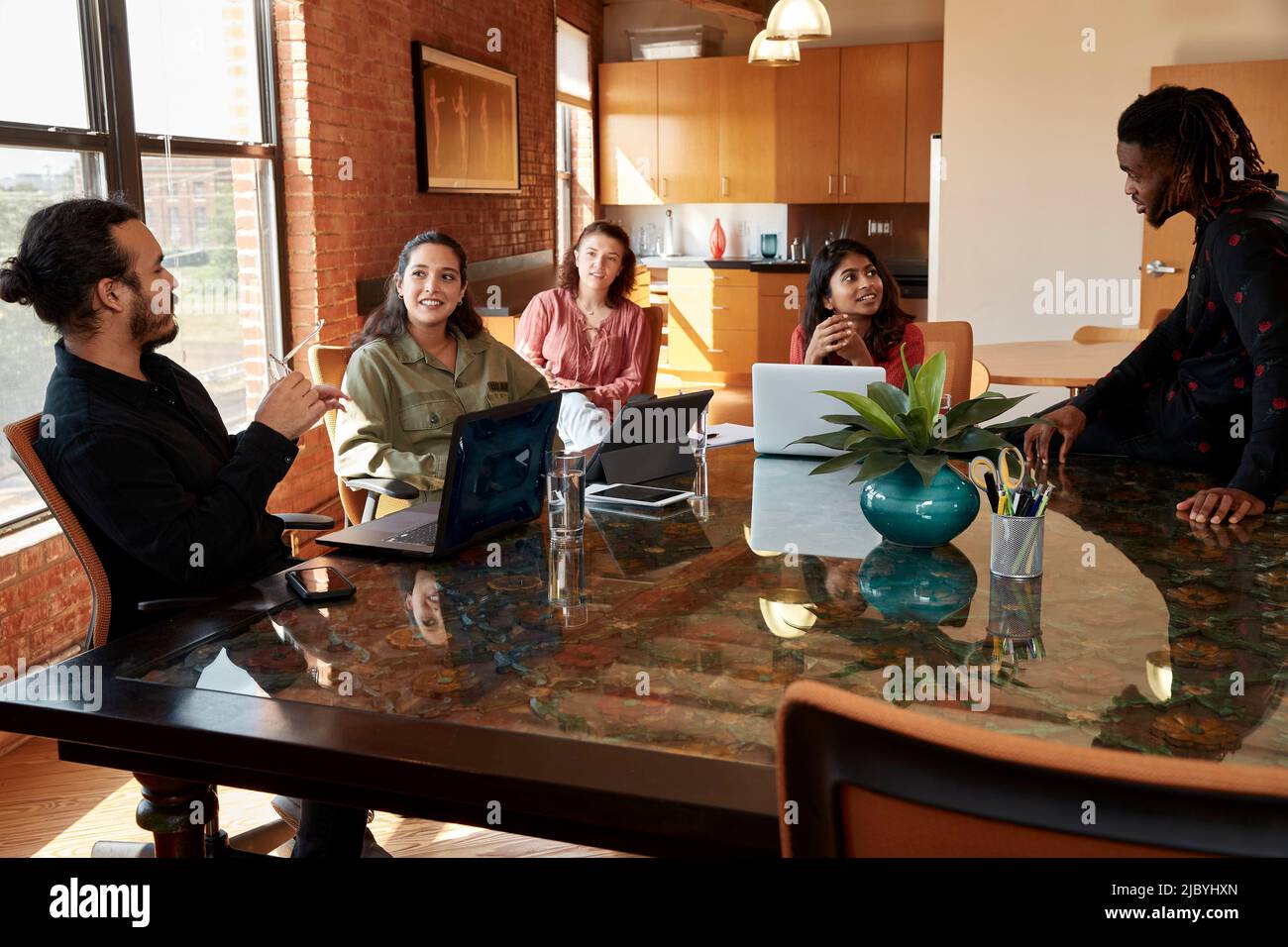 group of co-workers sitting at large conference table with their ...