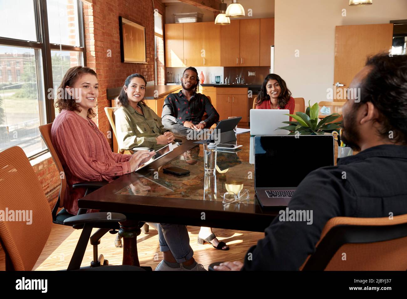 group of co-workers sitting at large conference table with their ...