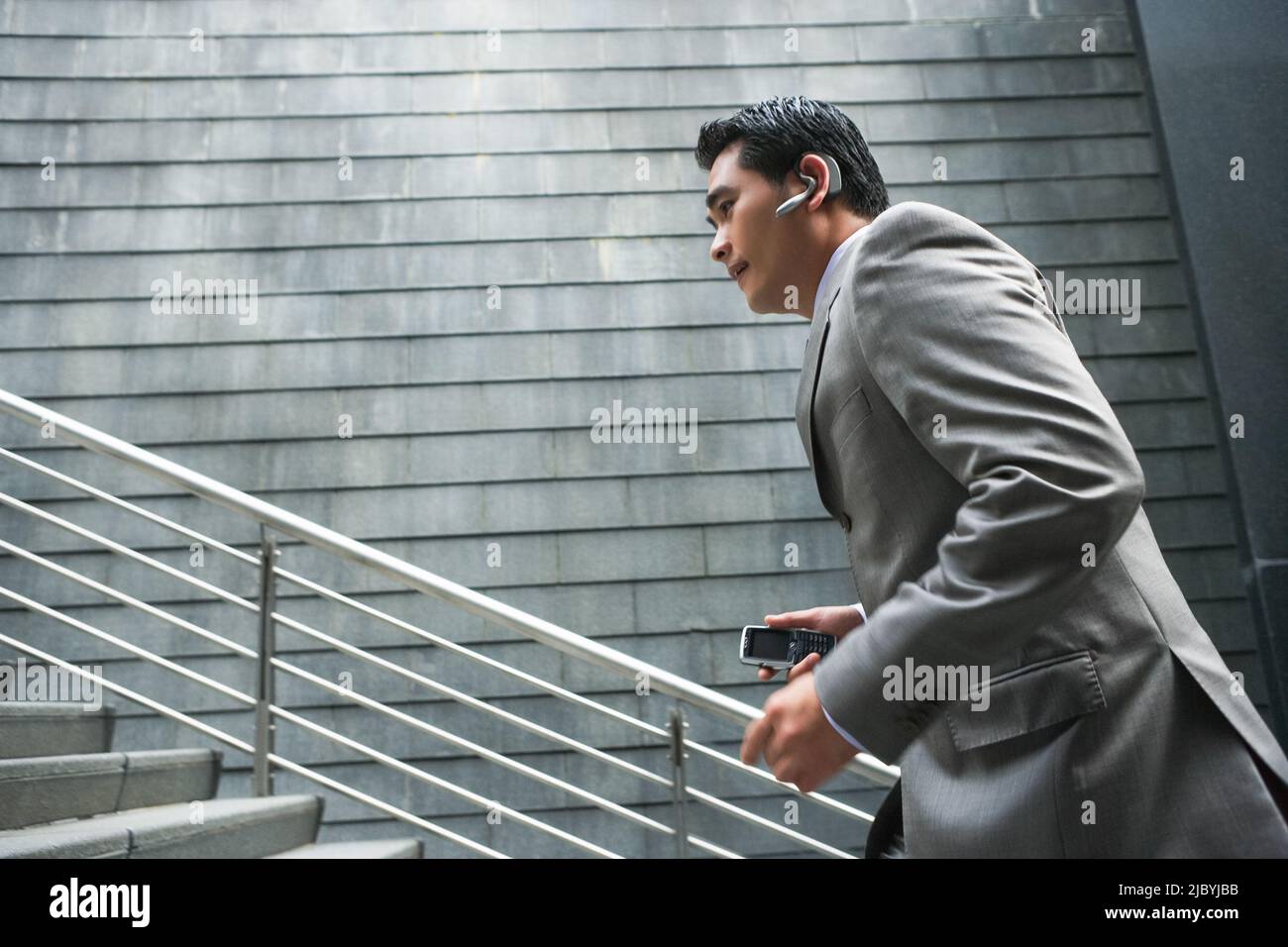 Chinese businessman with cell phone going up stairs Stock Photo - Alamy