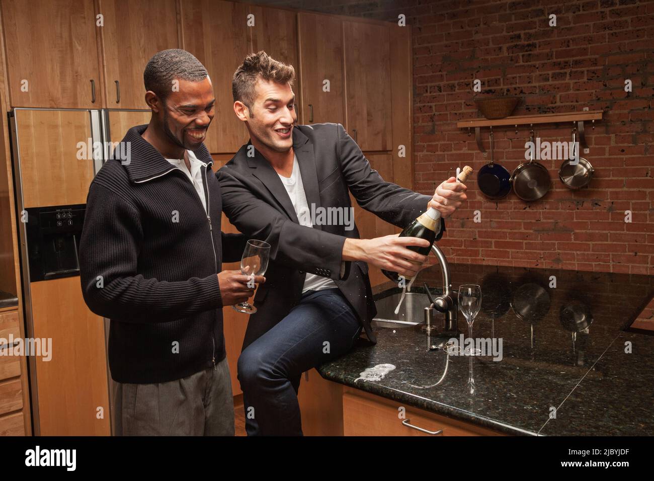 Gay couple drinking wine in kitchen Stock Photo - Alamy