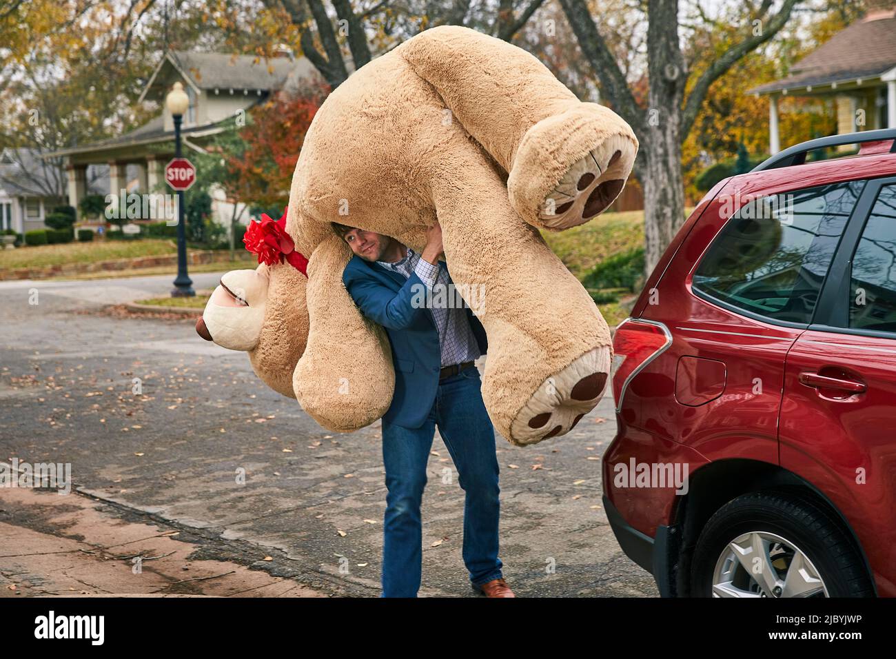 Wide shot of a man carrying a large teddy bear over his shoulder Stock ...