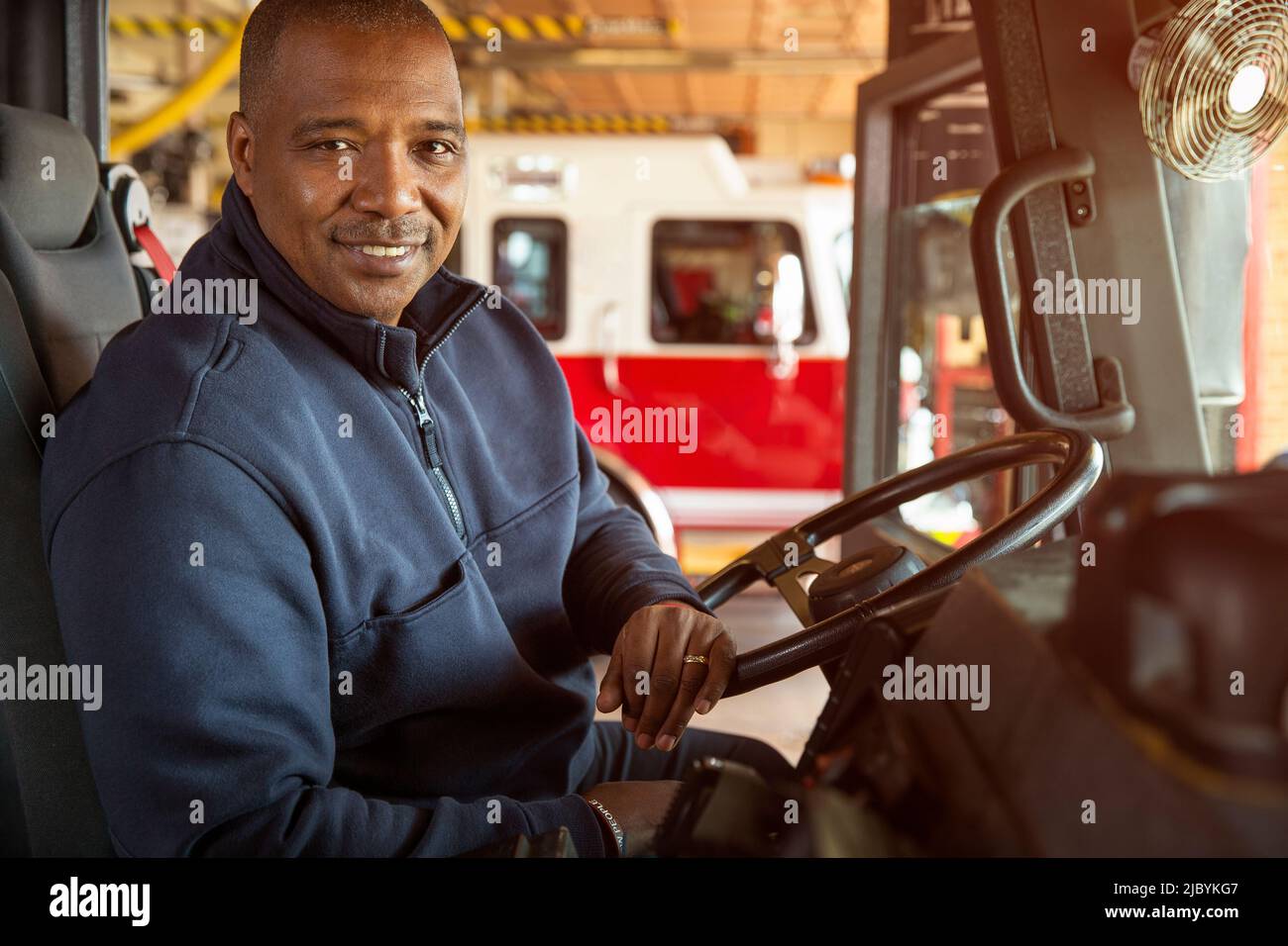 Portrait Of Fireman Sitting In Drivers Seat Of Firetruck Looking