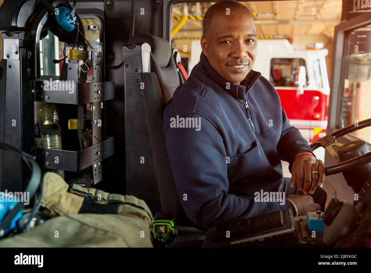 Portrait of Fireman Sitting in Drivers seat of firetruck looking ...