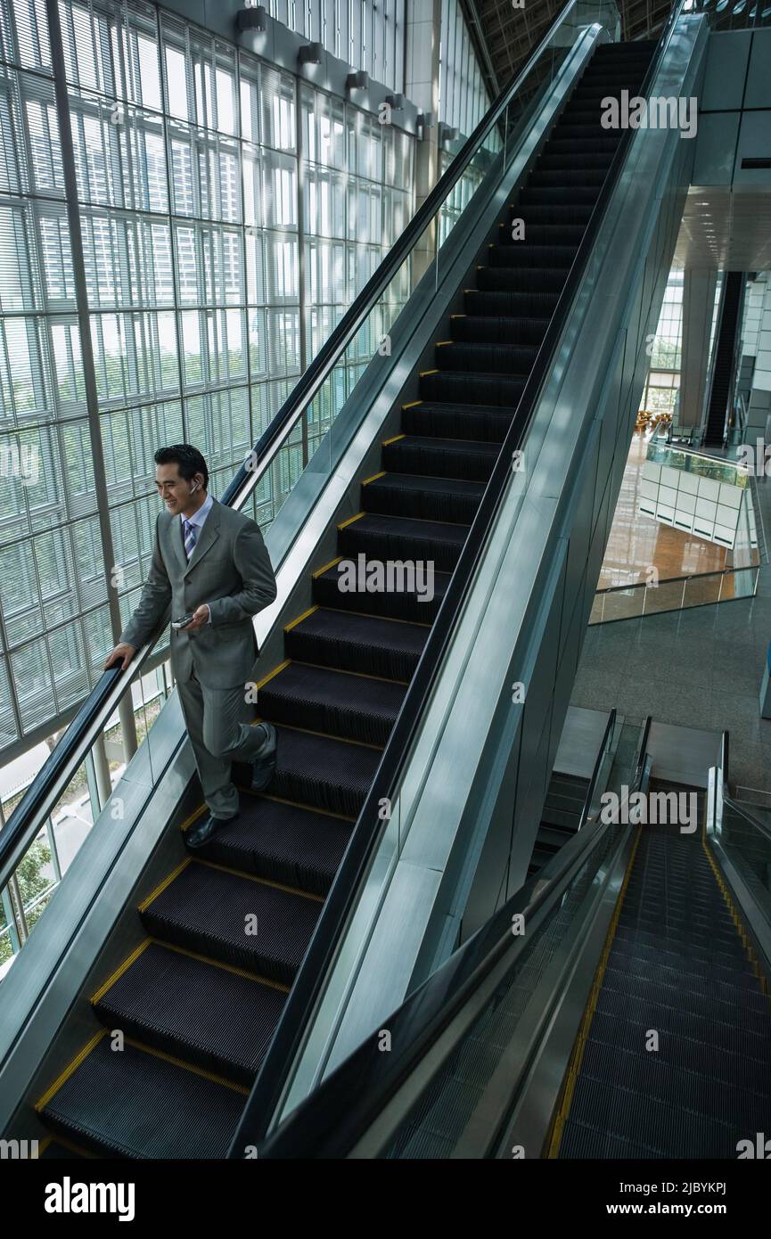 Chinese businessman holding cell phone on escalator Stock Photo - Alamy