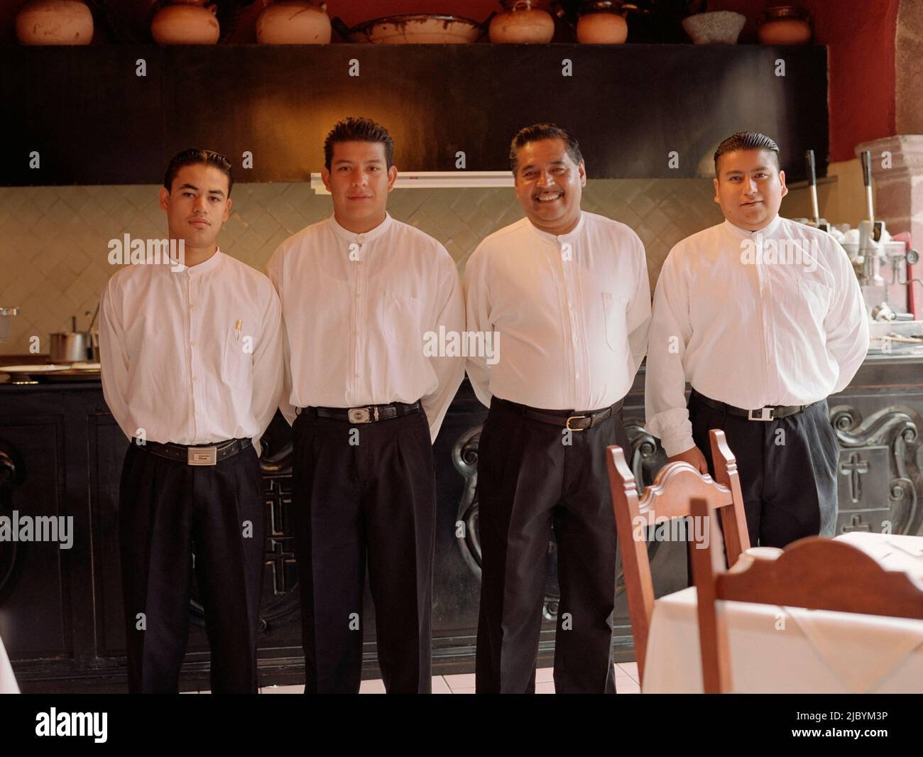 Four men standing in a row in restaurant Stock Photo - Alamy