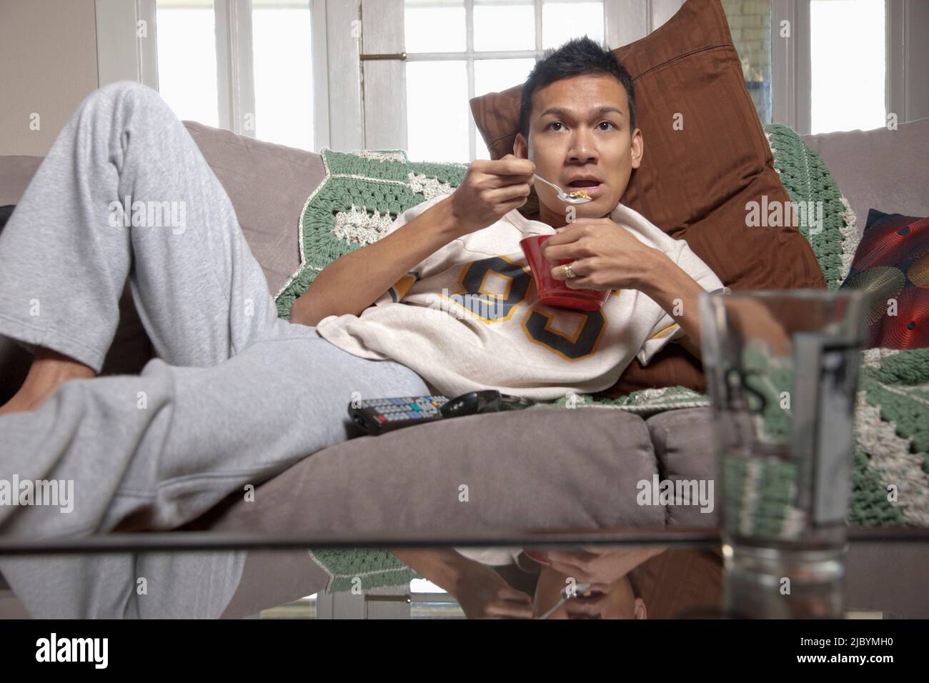 Lazy man eating on sofa and watching television Stock Photo - Alamy