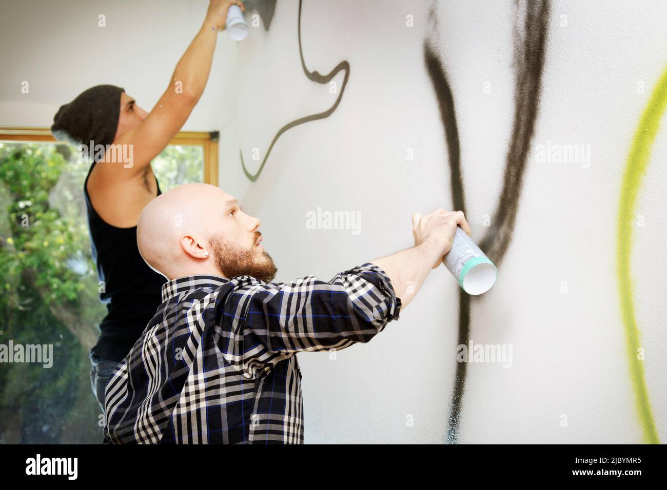 Men tagging wall with graffiti Stock Photo - Alamy