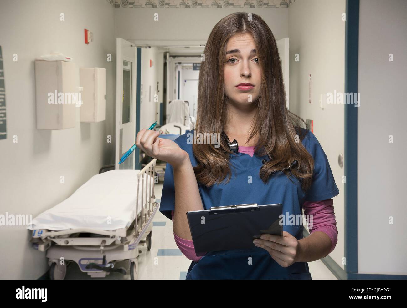 Overworked nurse holding clipboard in hospital hallway Stock Photo - Alamy