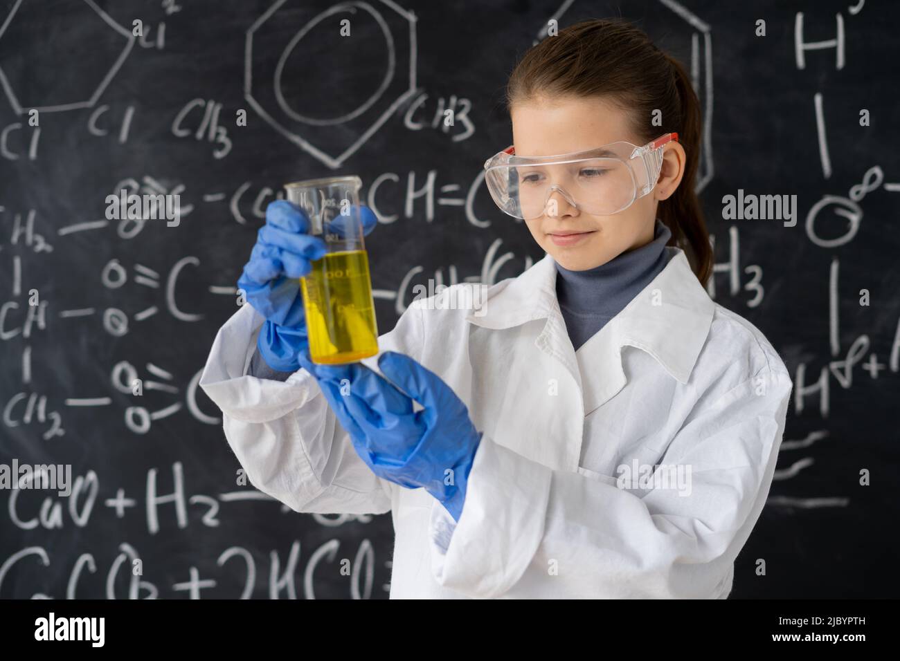 serious scientist child with glasses in lab coat with chemical flasks ...