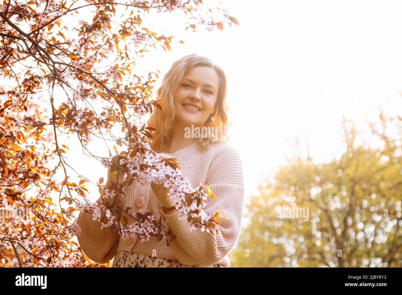 Portrait of young woman with fair hair wearing pink cardigan, dress ...