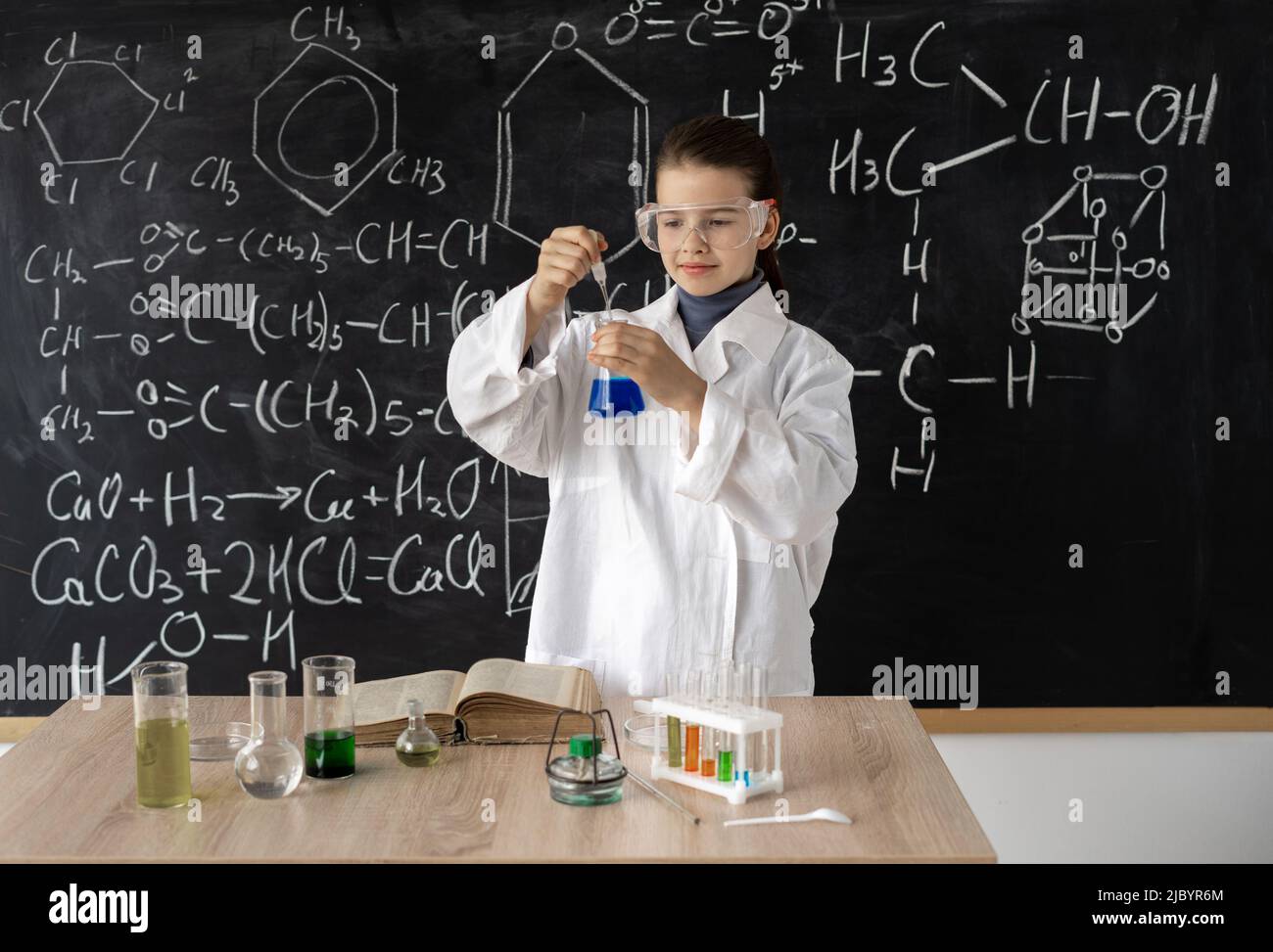 scientist child in lab coat with chemical flasks, blackboard background ...