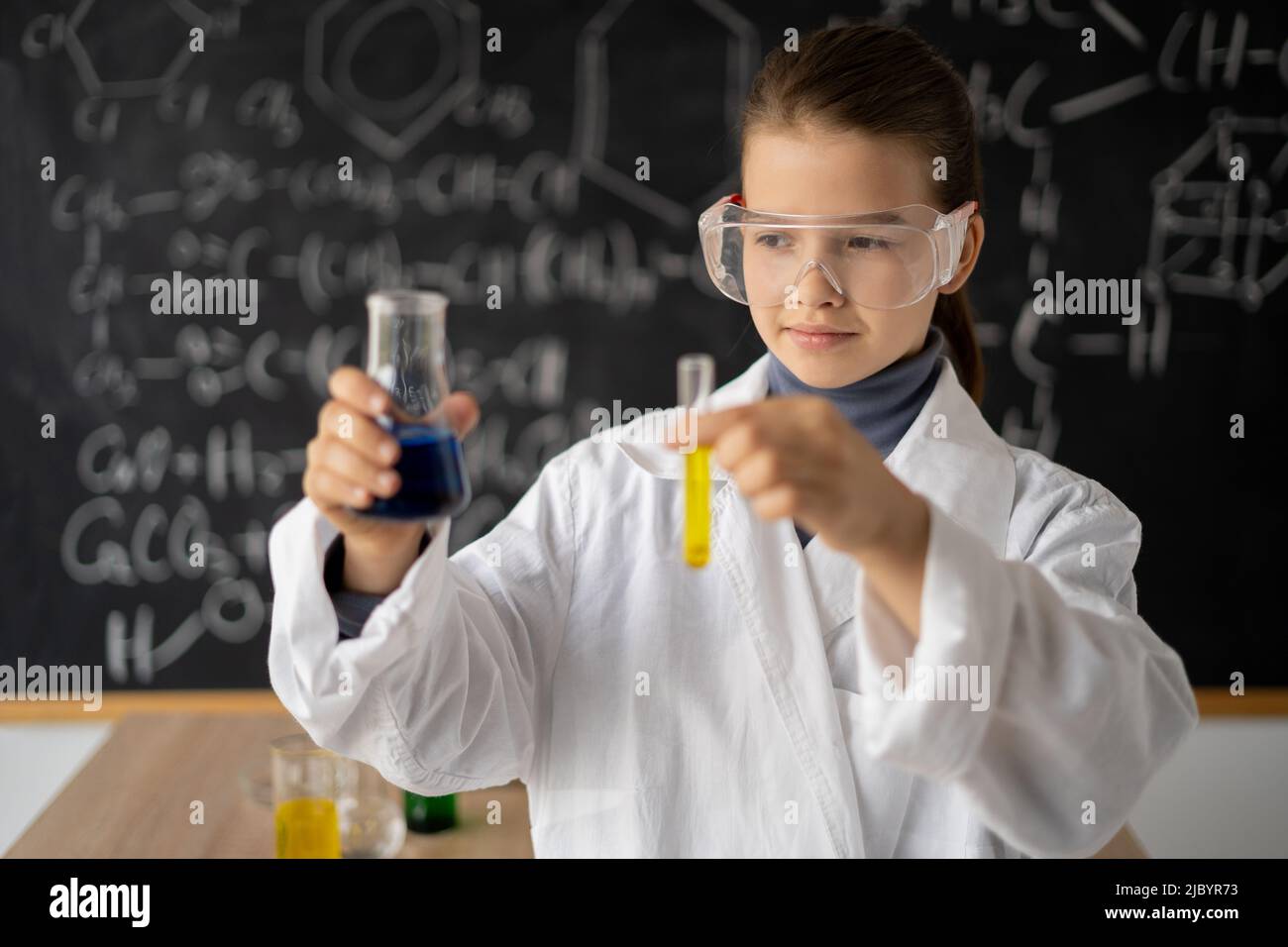 little scientist girl with glasses in lab coat with chemical flasks, on ...