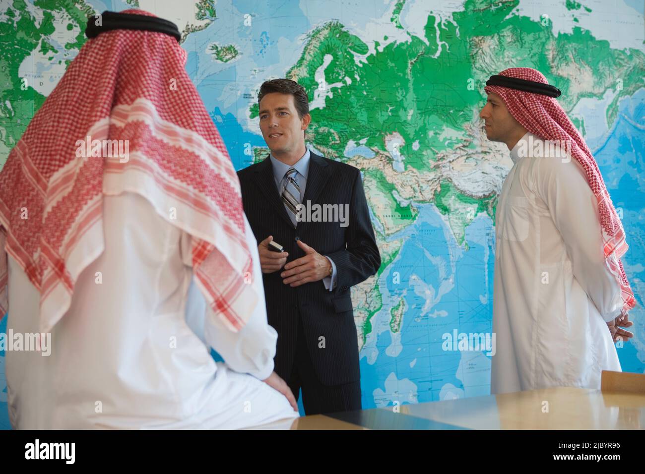 Middle Eastern businessman talking to men in traditional clothing Stock ...