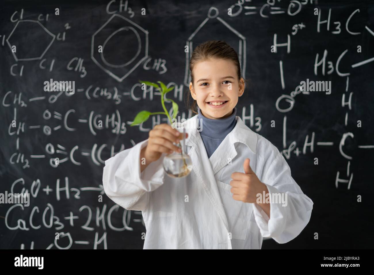 Young student holding a small plant in a flask at elementary sciences ...