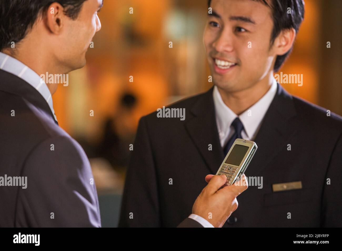 Businessmen talking, one with cell phone Stock Photo - Alamy