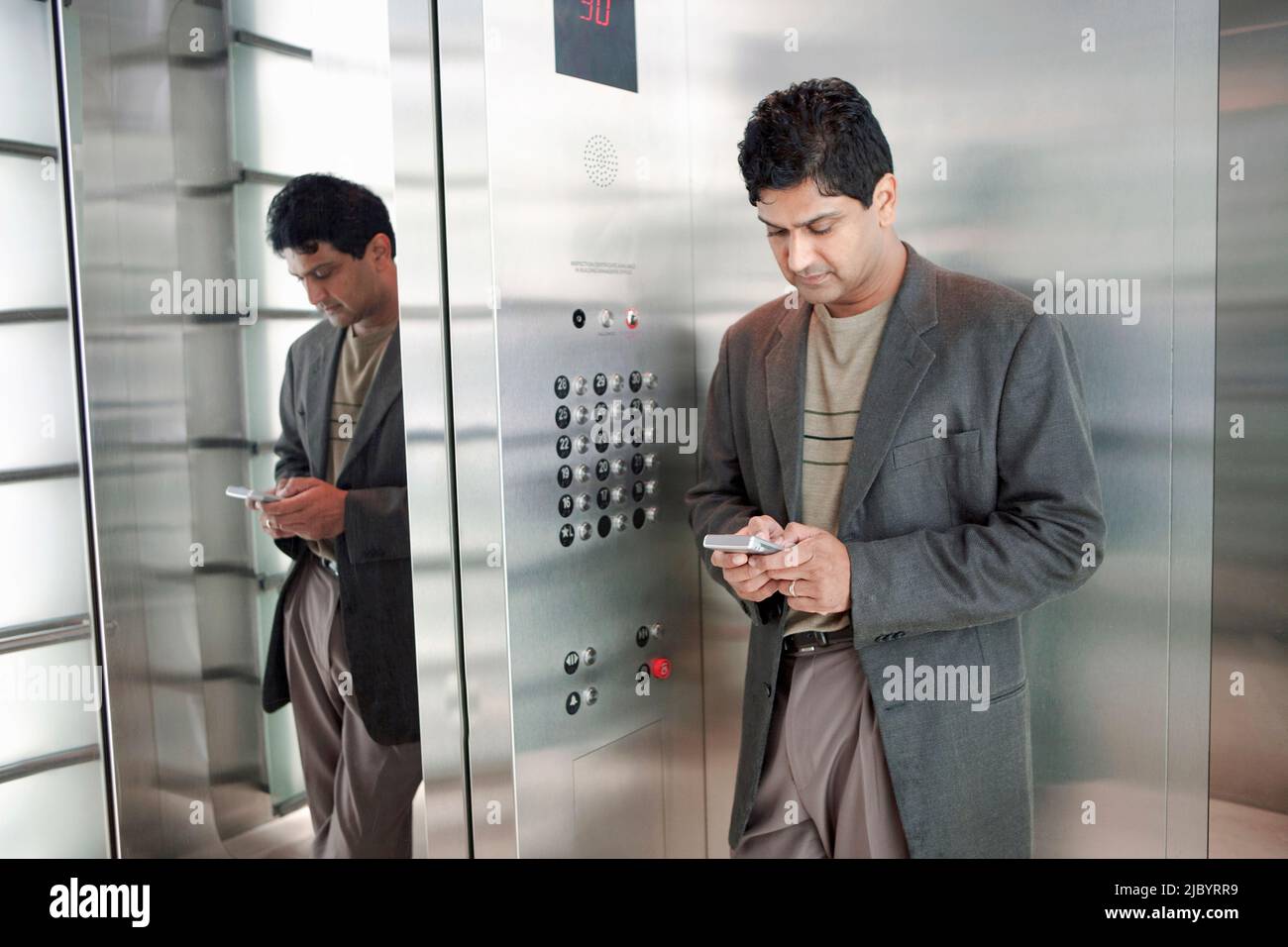 Indian businessman text messaging on cell phone in elevator Stock Photo ...