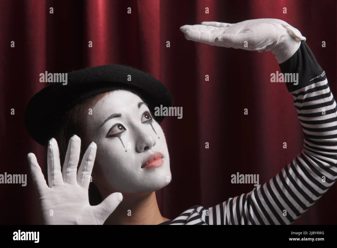Woman in mime costume with arms raised Stock Photo - Alamy