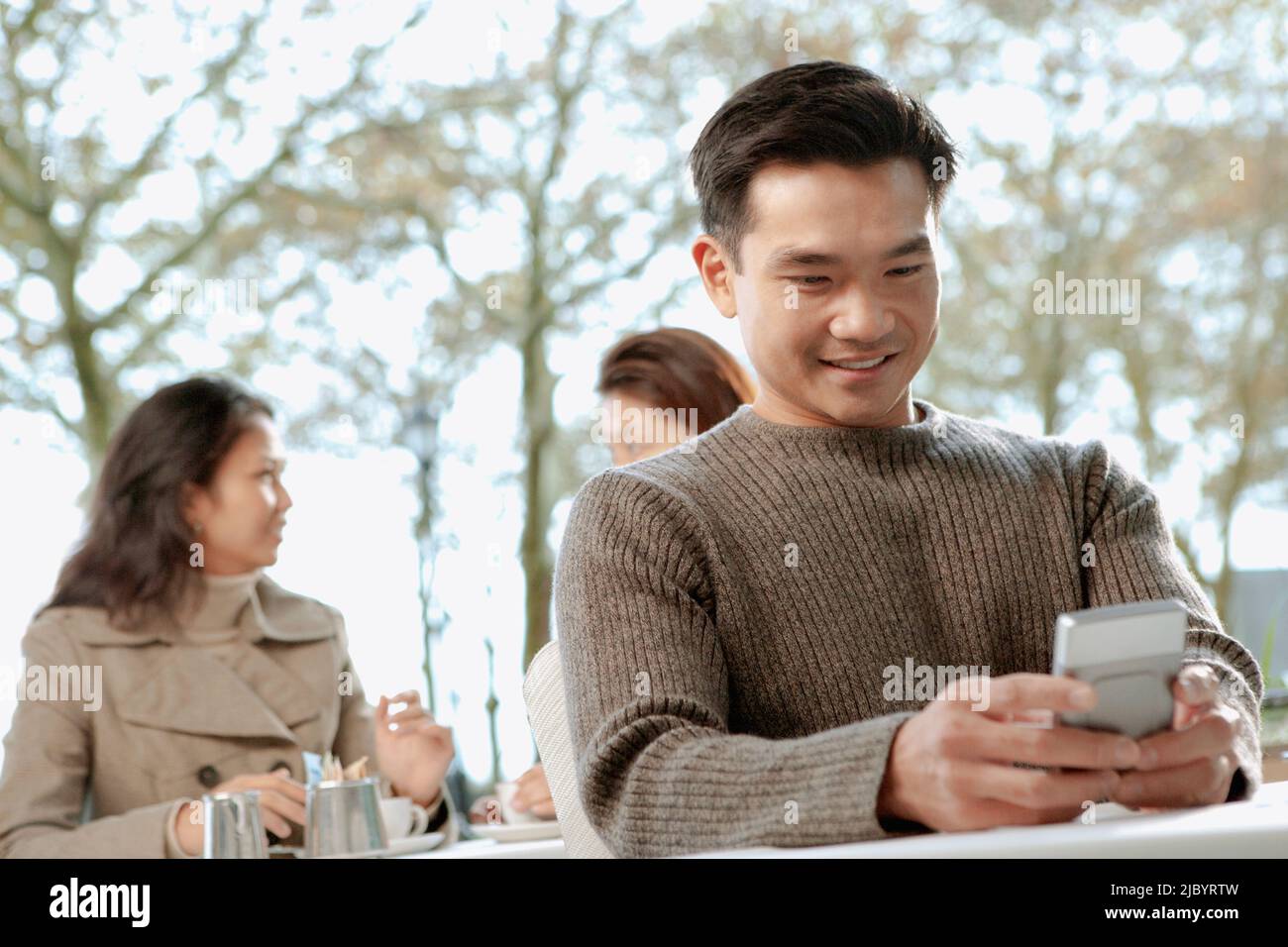 Asian man text messaging on cell phone in cafe Stock Photo - Alamy