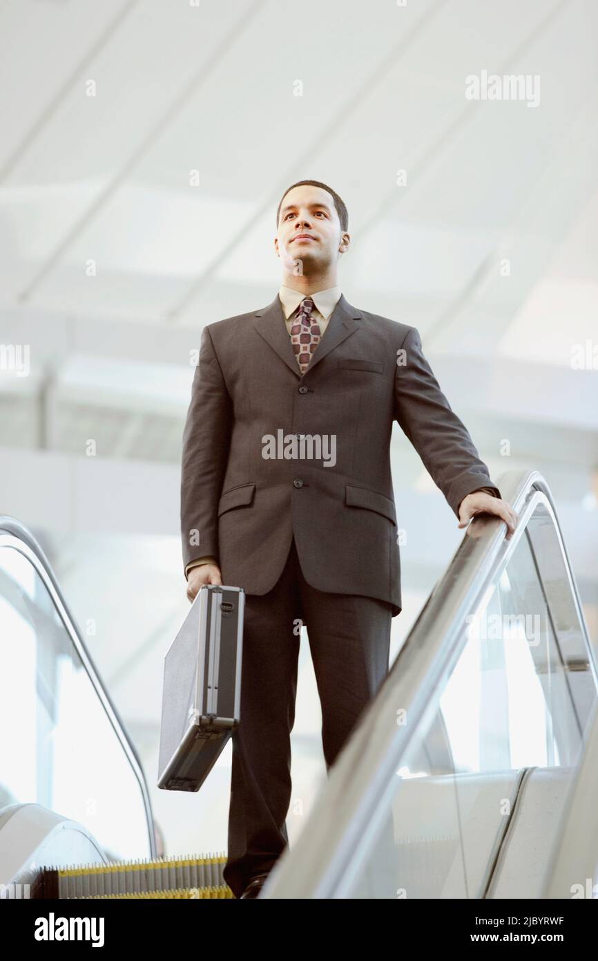 Hispanic businessman carrying briefcase on escalator Stock Photo - Alamy