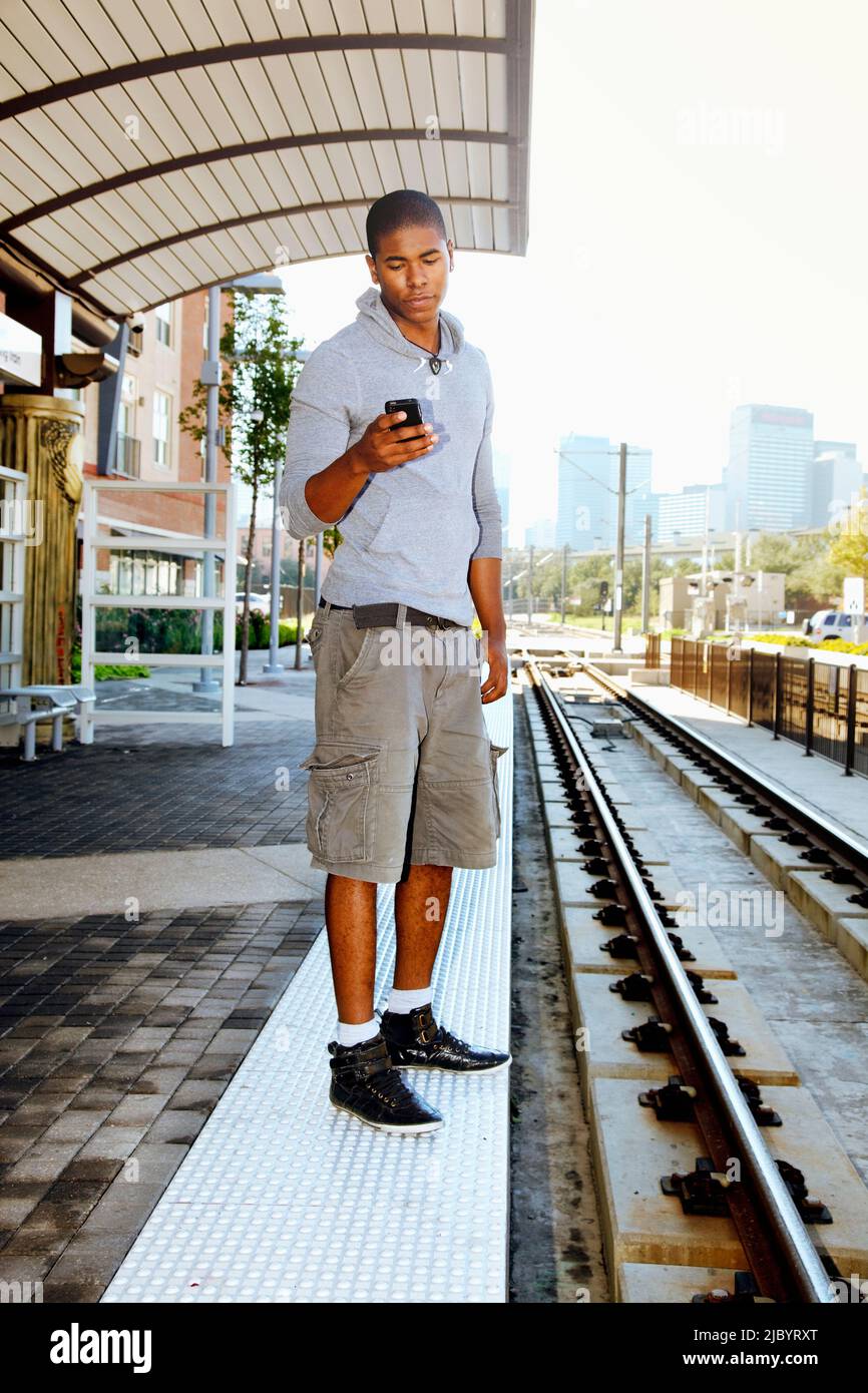 Man using cell phone on train platform Stock Photo - Alamy