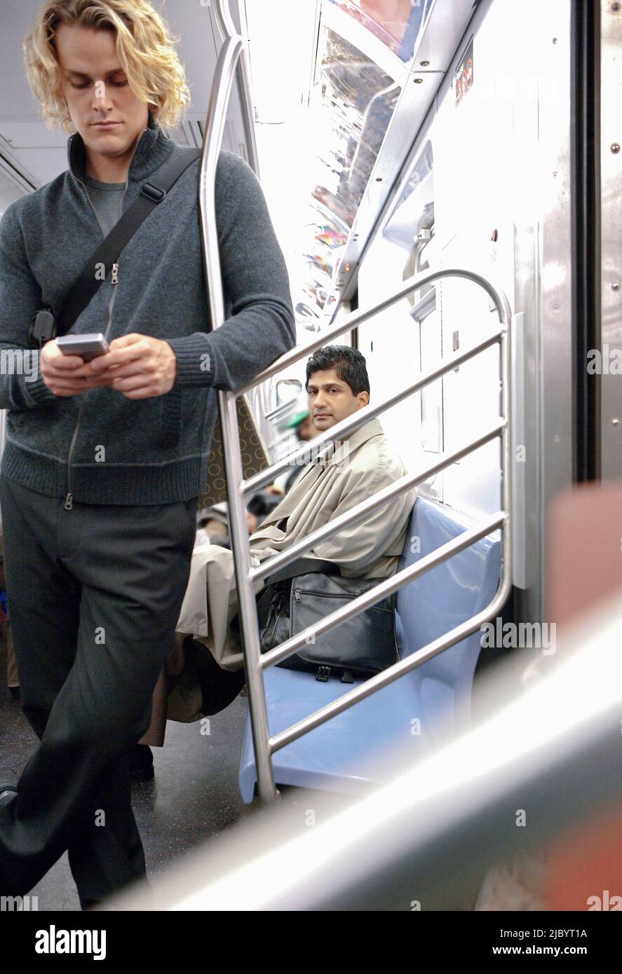 Caucasian businessman text messaging on cell phone on subway train ...