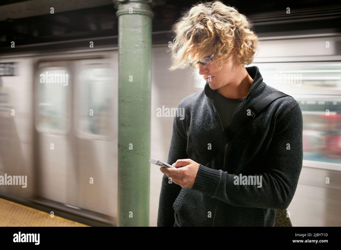 Caucasian man text messaging on cell phone in subway Stock Photo - Alamy