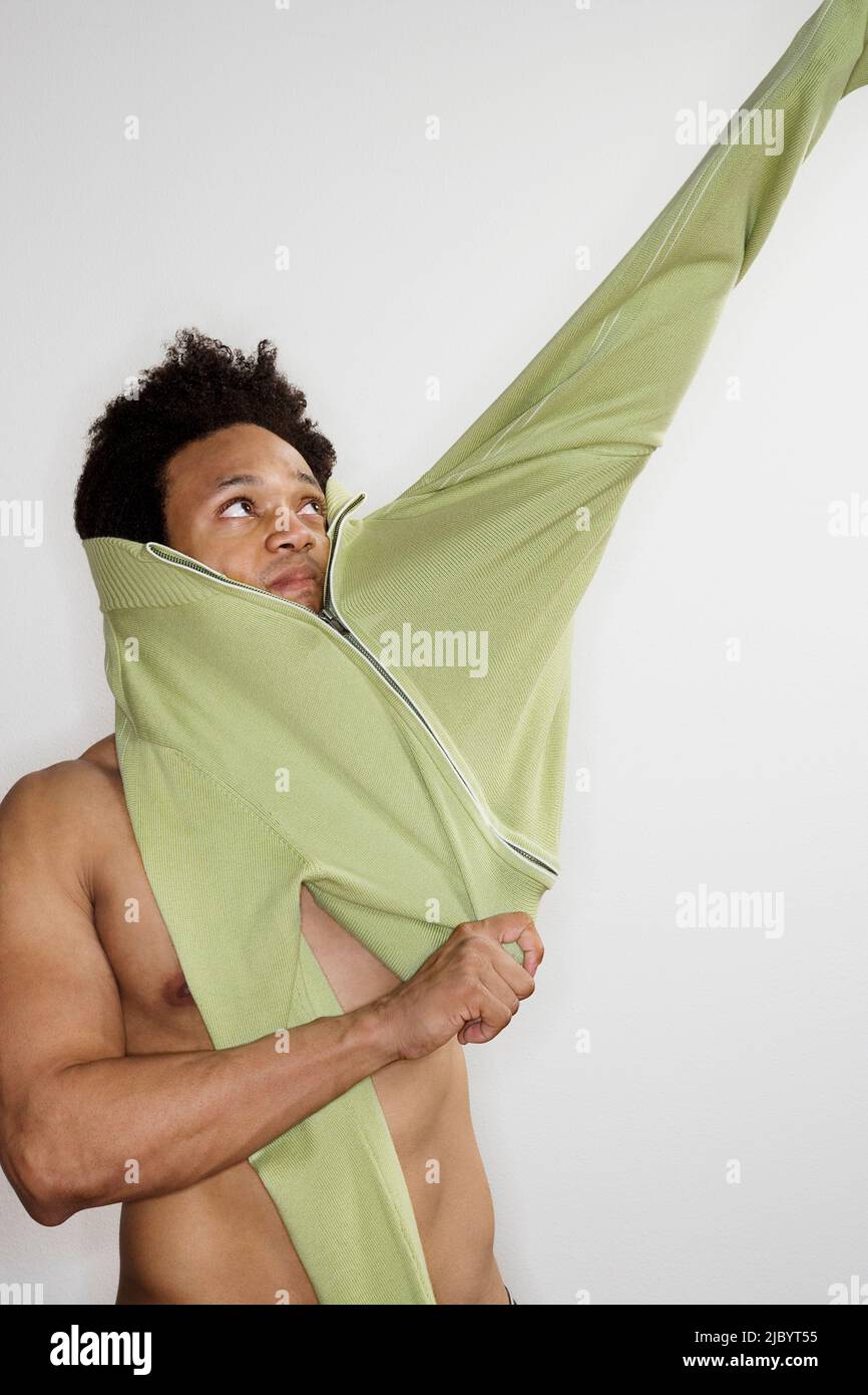 Black man pulling on sweater Stock Photo - Alamy