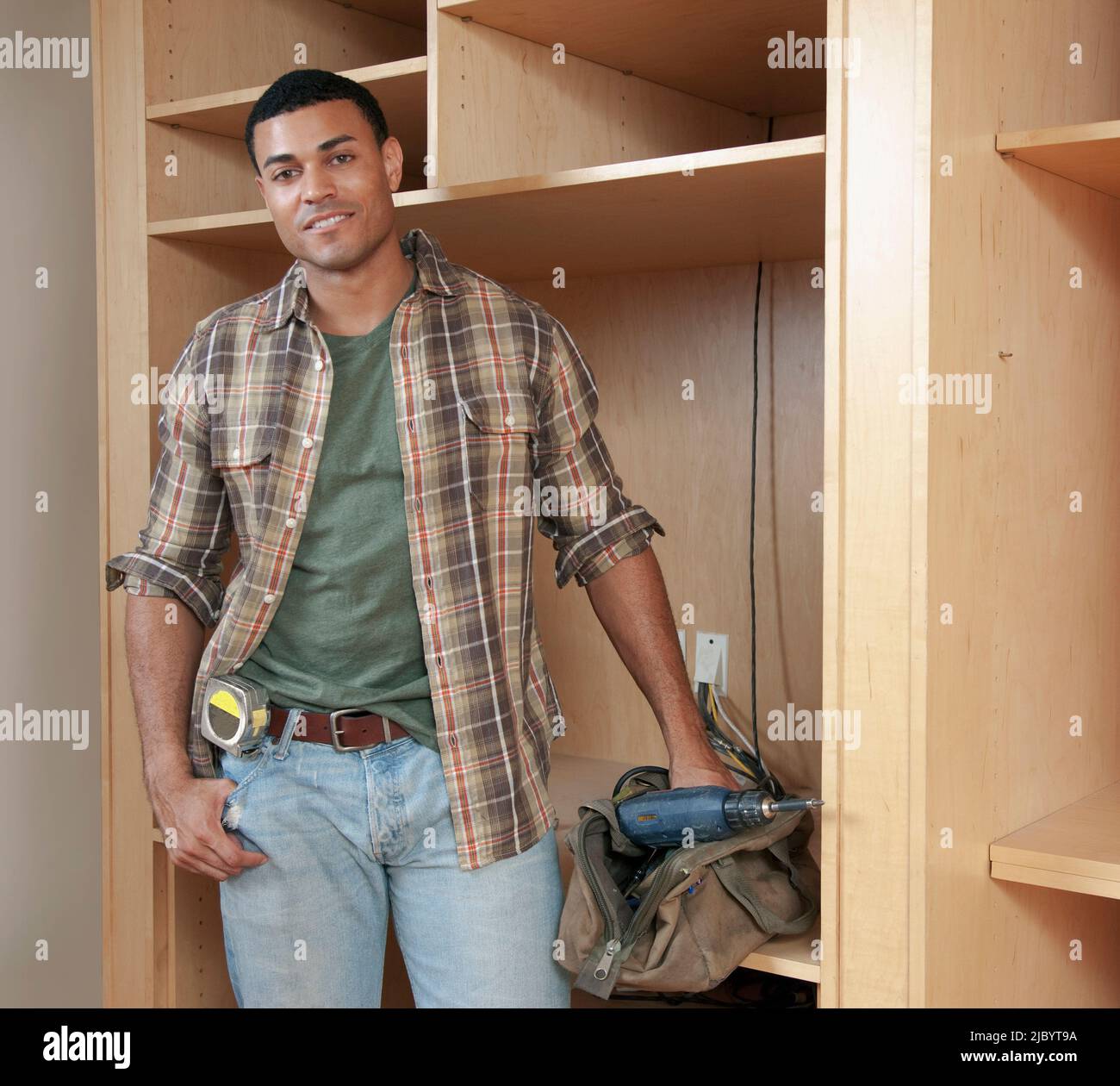 Mixed race man building cabinet Stock Photo - Alamy